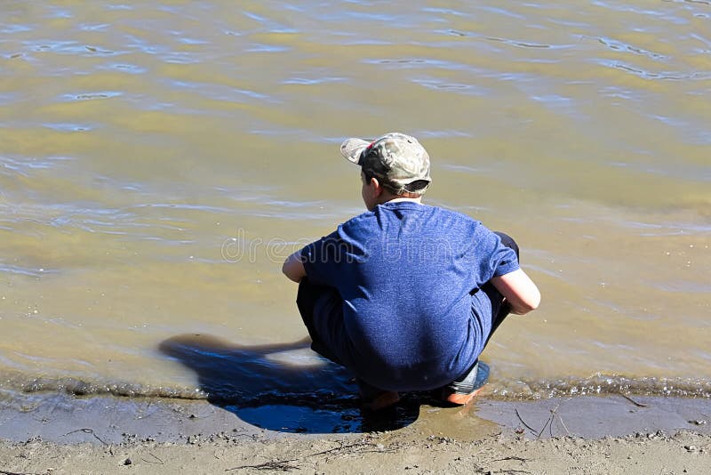A Young Boy Squats at the Water Edge Stock Image - Image of river ...