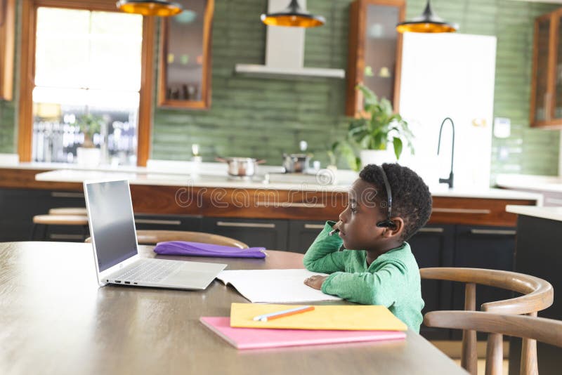 Young Boy Studying Online at Home, Focused on Laptop and Taking Notes ...