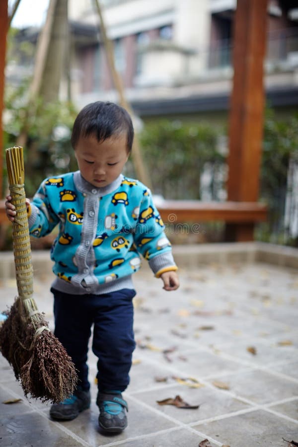 Young boy sweeping leaves stock image. Image of baby - 63241995