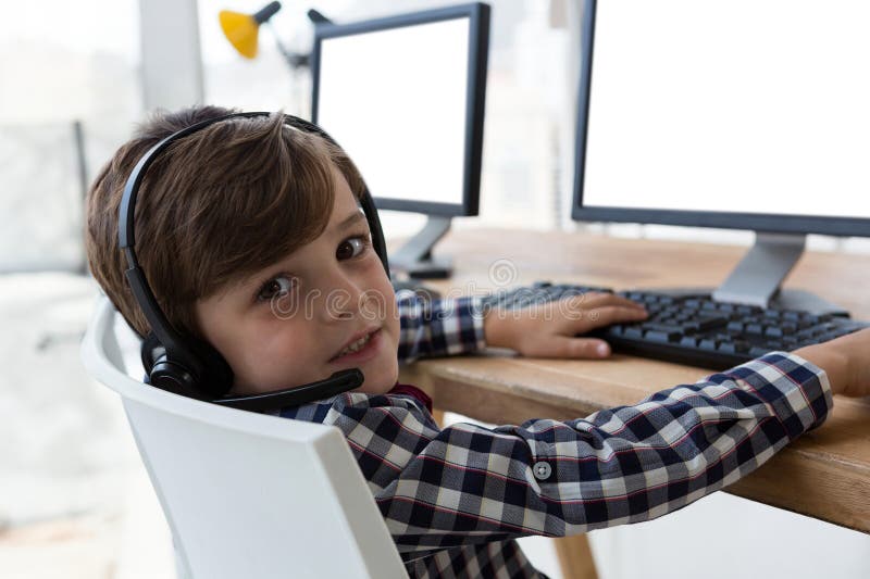 Young Boy Using Computer with Headset in Modern Home Office, Looking ...