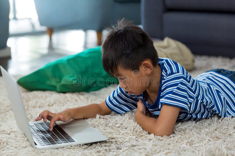 Young Boy Using Laptop on Carpet at Home, Focused on Screen Stock Image ...