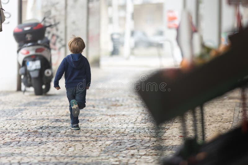 A Young Boy Walking Down a Cobblestone Street Stock Image - Image of ...