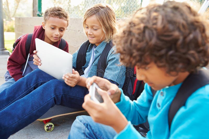 Young Boys Using Digital Tablets and Mobile Phones in Park Stock Image ...