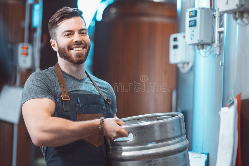 A Young Brewer in an Apron Holds a Barrel with Beer in the Hands Stock ...