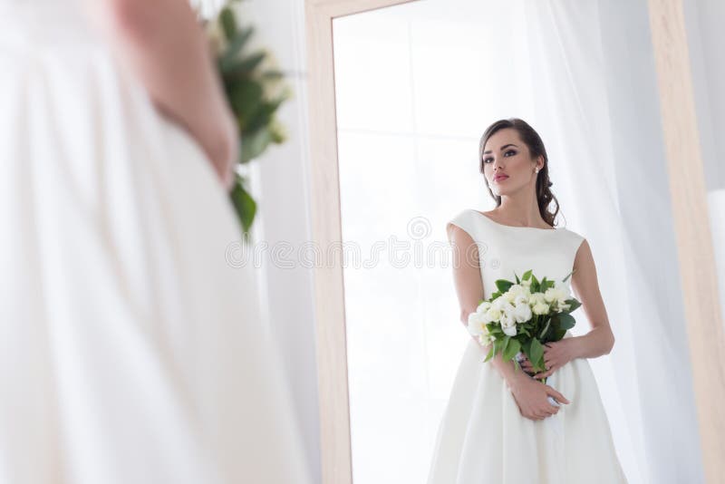 Young Bride in Dress with Wedding Bouquet Looking at Her Reflection ...