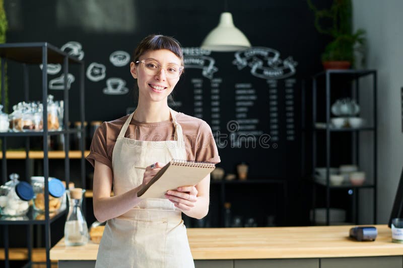 Young Brunette Female Clerk of Cafeteria Making Notes in Notepad Stock ...