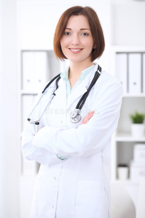 Young Brunette Female Doctor Standing With Arms Crossed And Smiling At