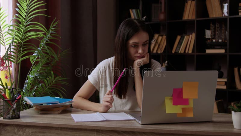 Young Brunette Lady is Browsing the Internet on Her Computer and ...