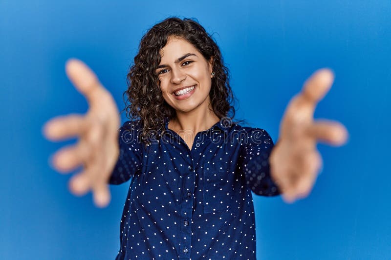 Young Brunette Woman With Curly Hair Wearing Casual Clothes Over Blue