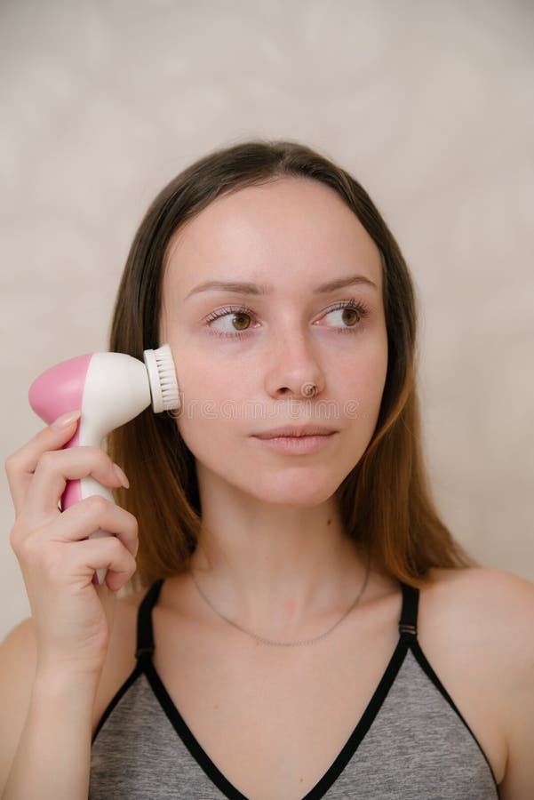 Young Woman Uses an Electric Brush To Deeply Clean Her Face Stock Photo ...