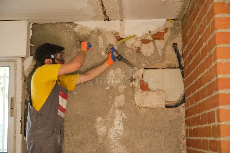 Young Builder Breaking Up a House Wall with a Hammer and a Chisel ...