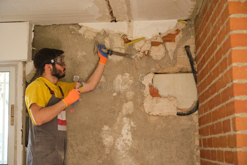 Young Builder Breaking Up a House Wall with a Hammer and a Chisel ...