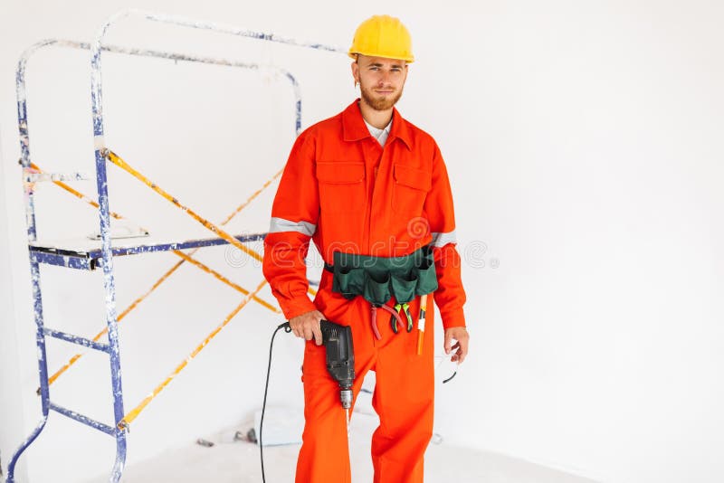 Young Builder in Orange Work Clothes and Yellow Hardhat Looking Stock ...