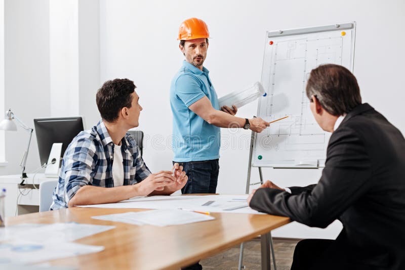 Young Builder Presenting a Blueprint To His Colleague Stock Image ...