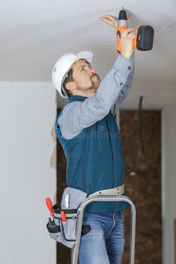 Young Builder Up Ladder Drilling Ceiling Stock Photo - Image of ...