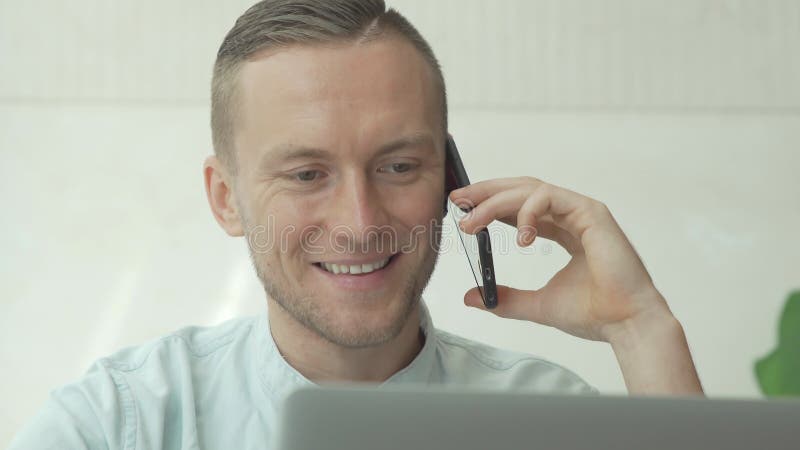 A Young Business Man Speaking on the Phone and Viewing E-mail on Laptop ...
