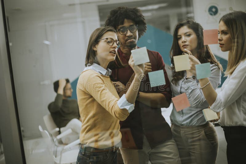 Young Business People Discussing in Front of Glass Wall Using Post it ...