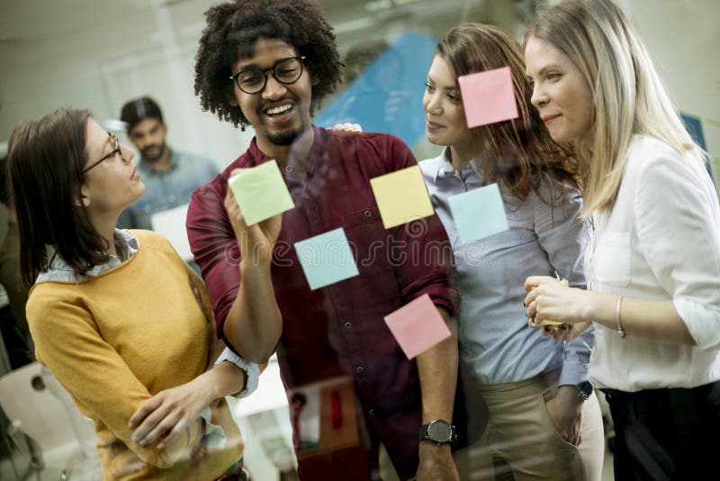 Young Business People Discussing in Front of Glass Wall Using Post it ...