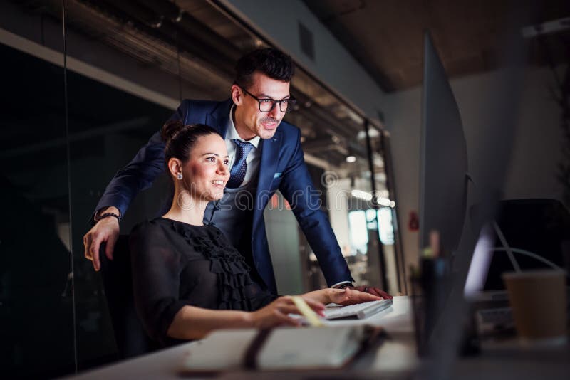 Young Business People in an Office at Night, Using Computer. Stock ...