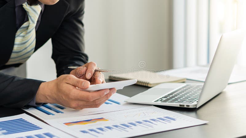 A Young Businessman Calculating the Machine on the Graph Document on ...