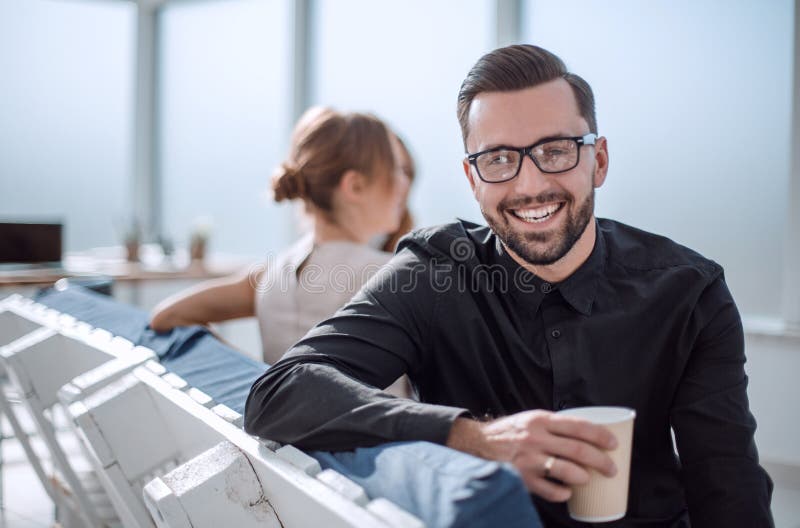 Young Businessman with a Cup of Coffee Sitting in a Modern Office ...