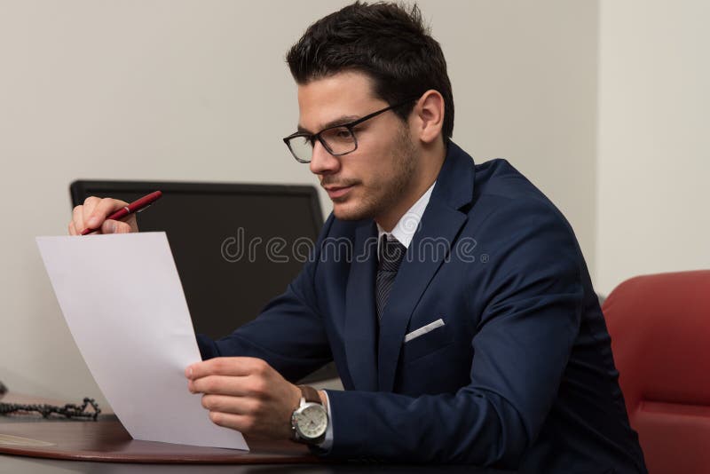 Young Businessman in Office Looking at Paper Stock Image - Image of ...