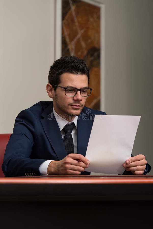 Young Businessman in Office Looking at Paper Stock Image - Image of ...