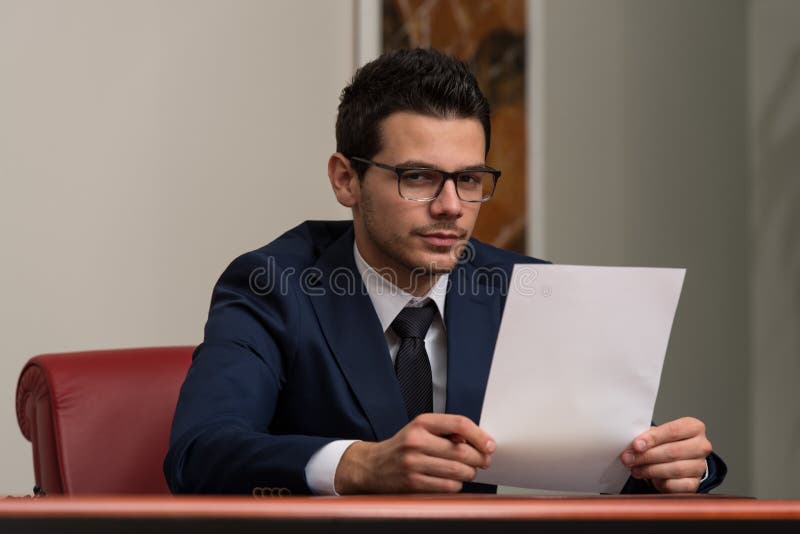 Young Businessman in Office Looking at Paper Stock Photo - Image of ...
