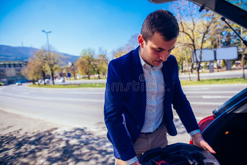 Young Businessman Pulling His Tools Out from the Back of His Car on a ...