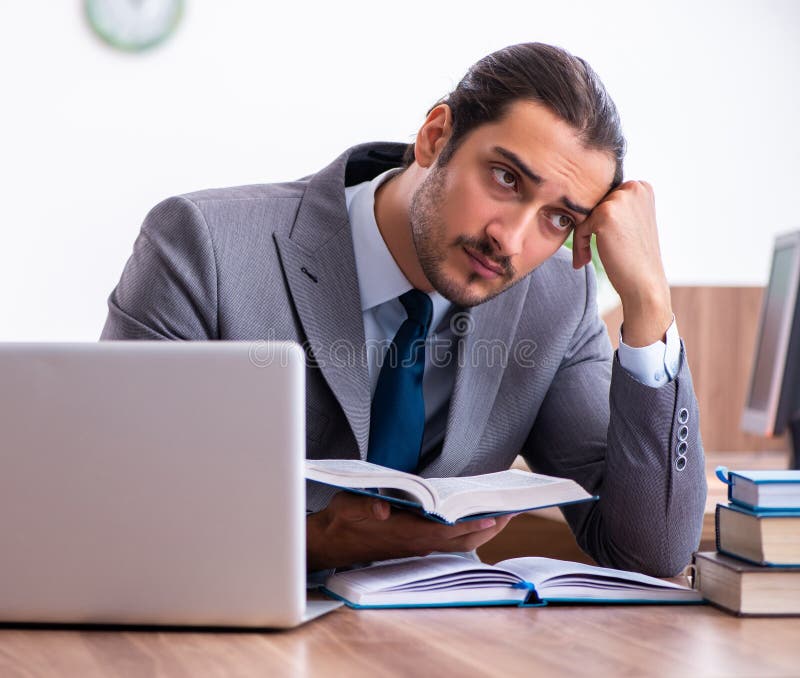 Young Male Businessman Reading Books at Workplace Stock Image - Image ...