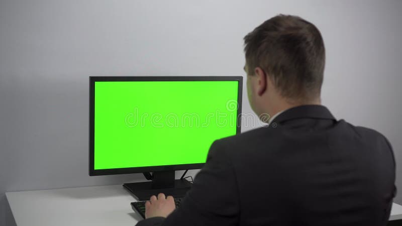 A Young Businessman is Sitting in Front of a Computer with a Green ...