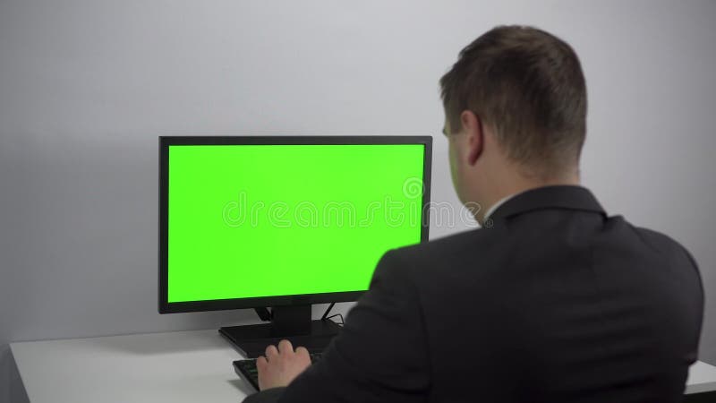 A Young Businessman is Sitting in Front of a Computer with a Green ...