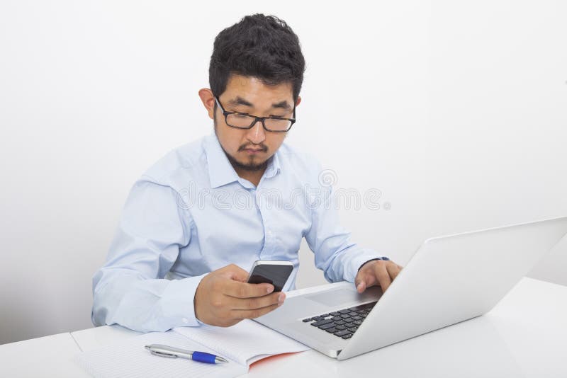 Young Businessman Using Cell Phone while Working at Desk in Office ...