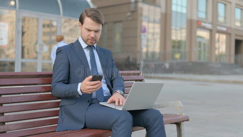 Businessman Using Smartphone and Laptop while Sitting Outdoor on Bench ...
