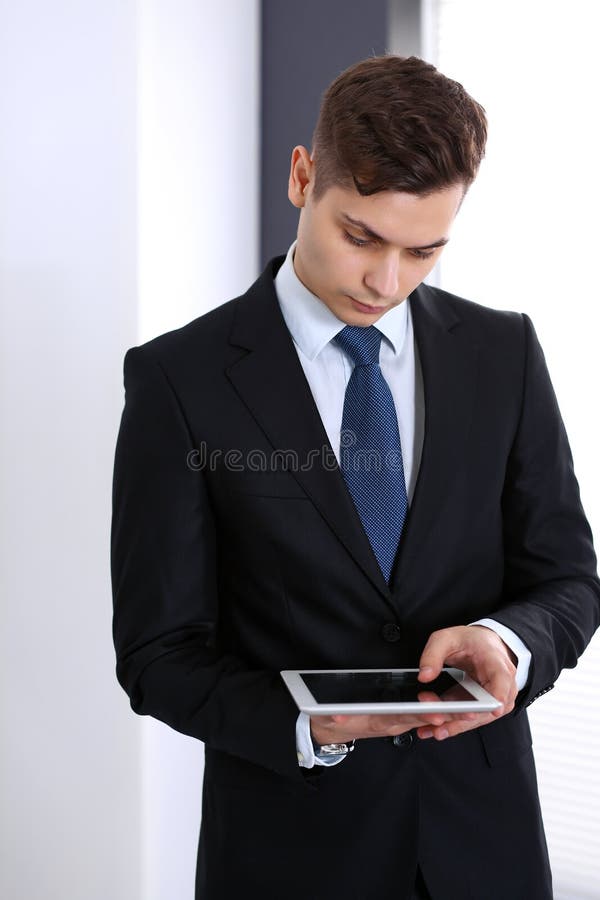 Young Businessman Using Tablet Computer while Standing Straight in ...