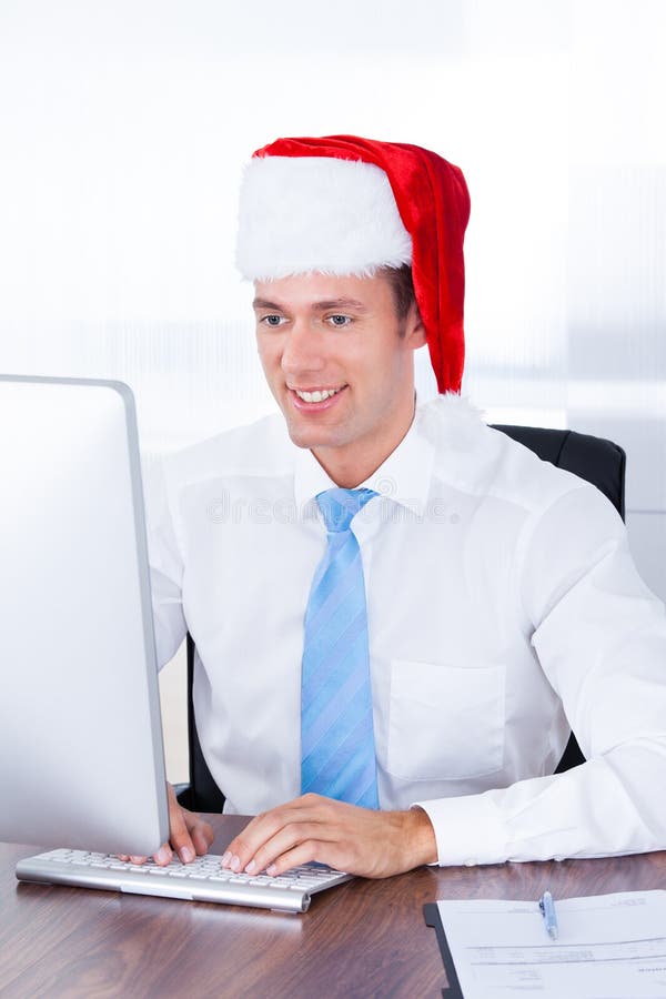 Young Businessman Wearing Santa Hat Using Computer in Office Stock ...