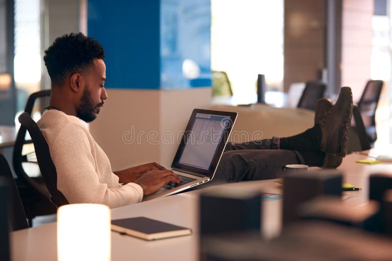 Young Businessman Working Late Sitting at Desk with Laptop in Modern ...