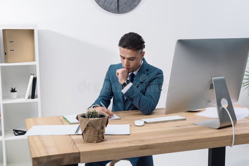Young Businessman Writing in Notebook while Working at Table with ...