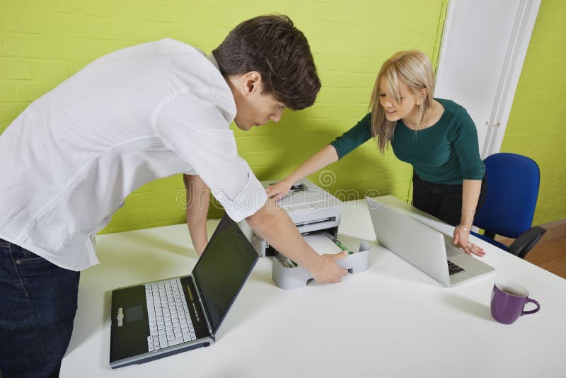 Young Businesspeople Setting Up Printer with Laptops at Desk Stock ... Young Businesspeople Setting Up Printer with Laptops at Desk Stock ...