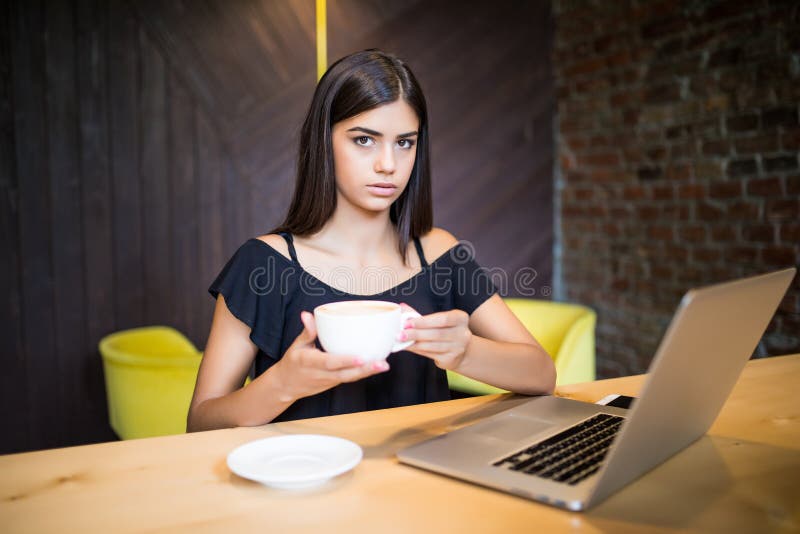 Young Woman Drinking Coffee and Using Computer in Cafe Stock Photo ...