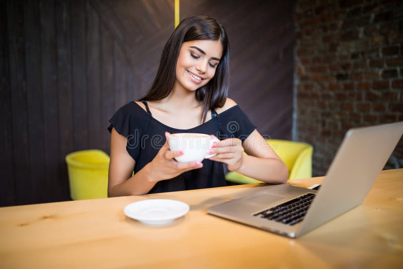 Young Woman Drinking Coffee and Using Computer in Cafe Stock Image ...