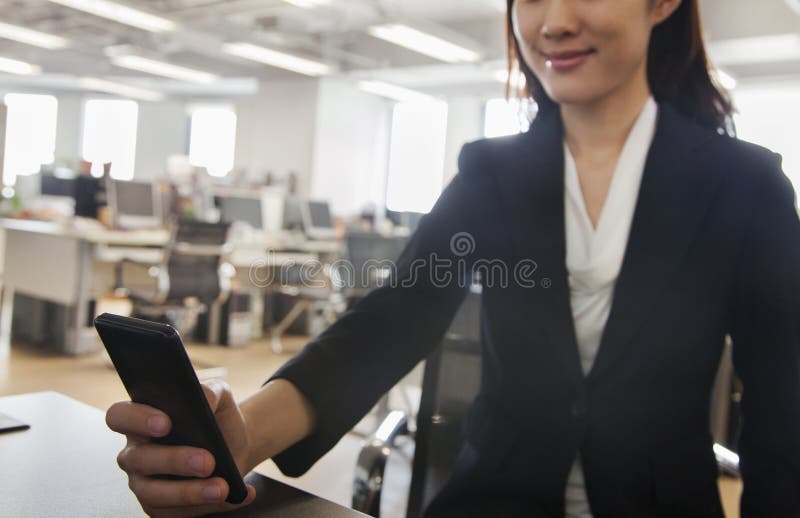 Young Businesswoman Smiling and Using Her Phone at the Office Stock ...
