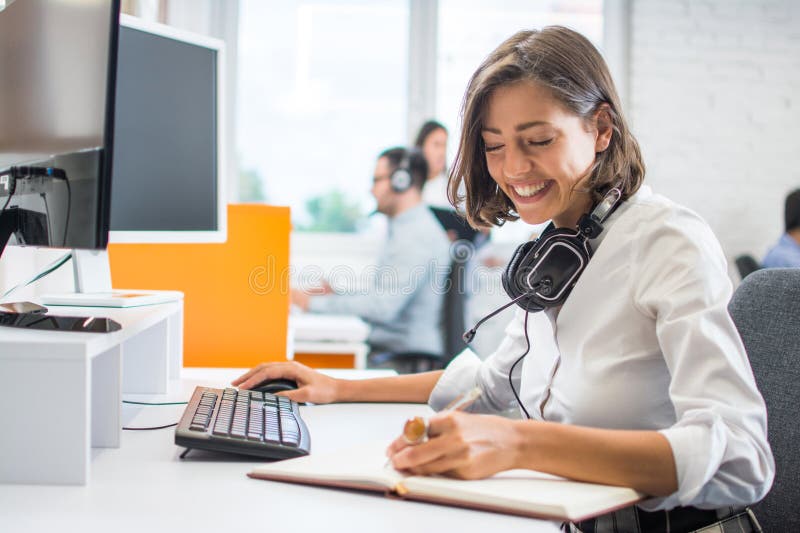 Young Businesswoman Working in Front of Computer, Writing Notes To ...