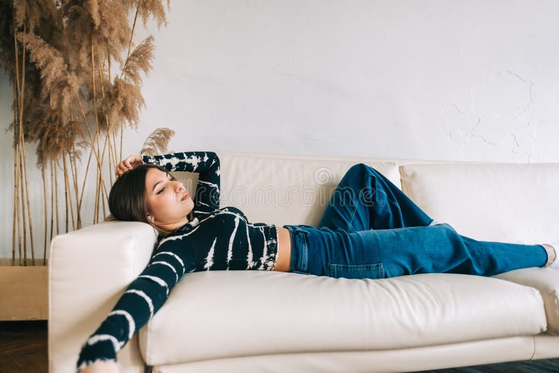 Young Calm Caucasian Woman Relaxing Lying on Comfortable Sofa in Modern ... Young Calm Caucasian Woman Relaxing Lying on Comfortable Sofa in Modern ...