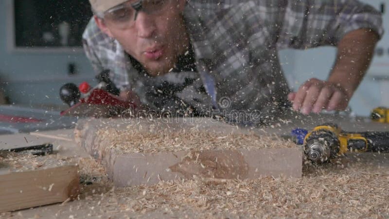A Young Carpenter is Cleaning a Workbench from Sawdust in a Carpentry ...
