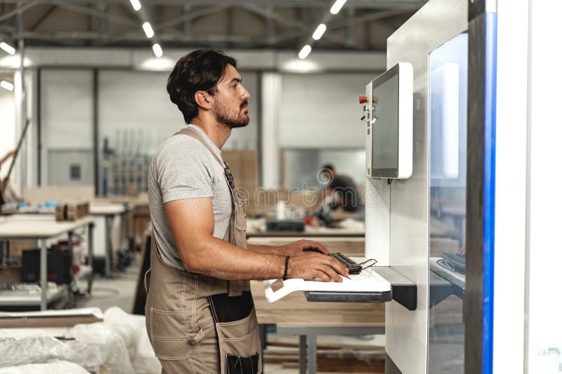 Young Carpenter Operating Machine for Wood Processing at a Furniture ...