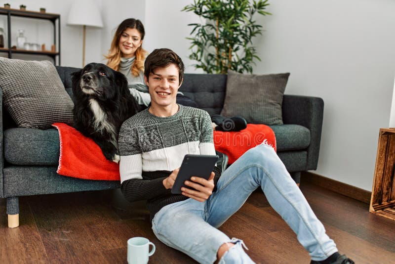 Young Caucasian Couple Smiling Happy with Dog Using Touchpad at Home ...