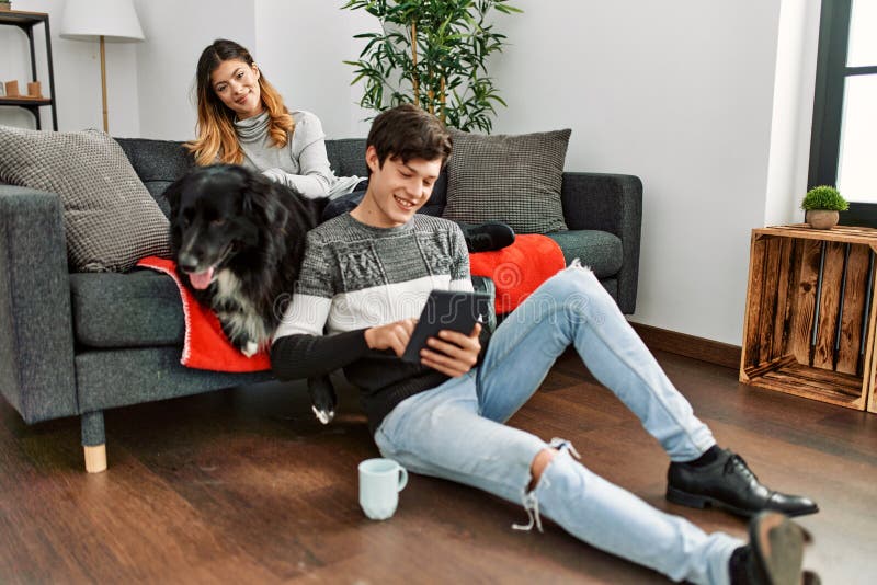 Young Caucasian Couple Smiling Happy with Dog Using Touchpad at Home ...