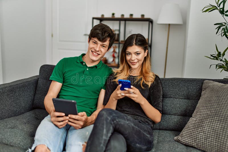Young Caucasian Couple Smiling Happy Using Touchpad and Smartphone at ...