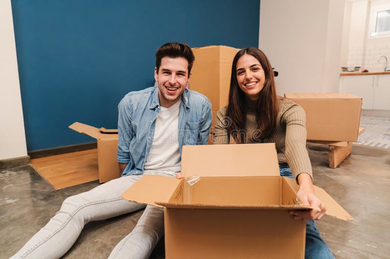 Young Caucasian Couple Smiling Making A Move To Their New Home Using